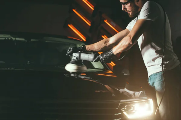 Car detailing - man with orbital polisher in auto repair shop ...