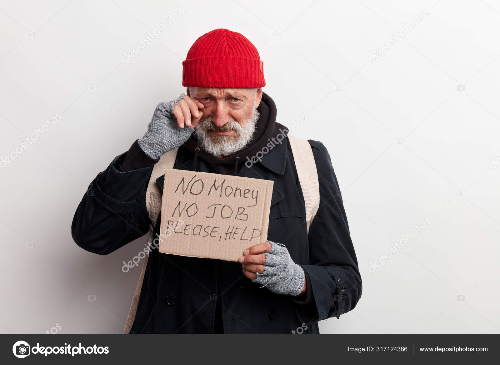Poor old-aged bum in red hat and street wear holding cardboard sign ...