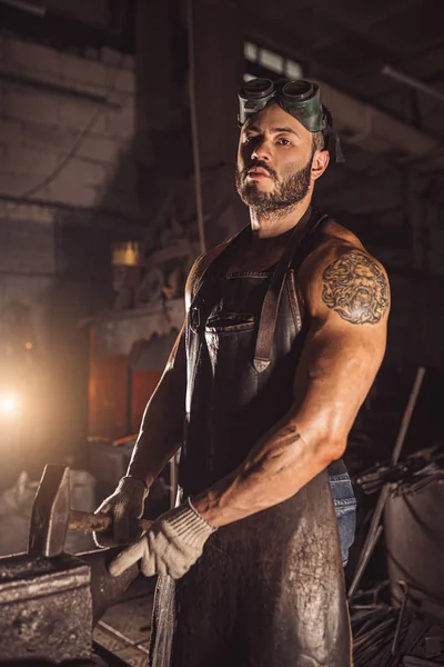 Portrait of young caucasian blacksmith man in leather black uniform ...