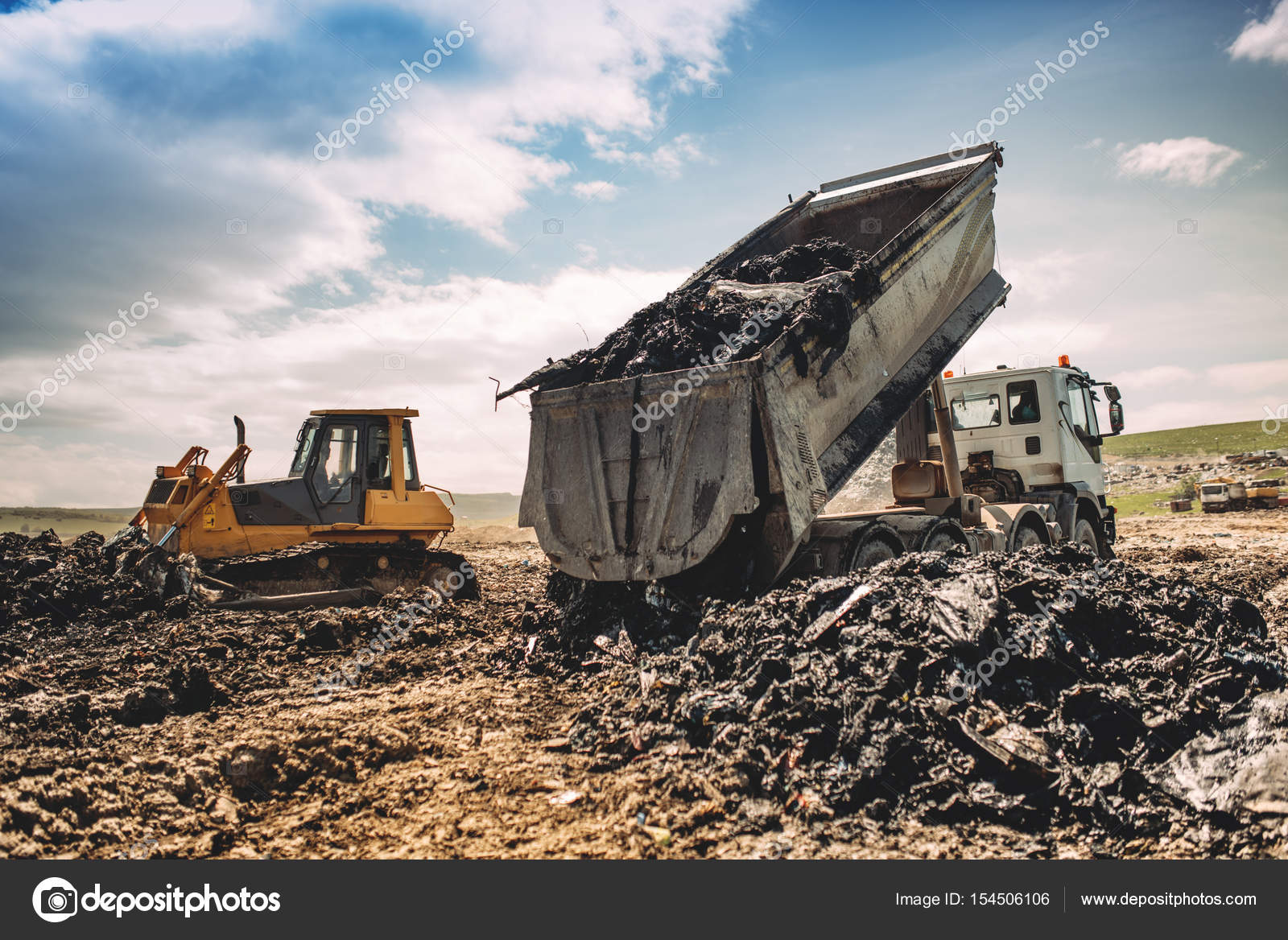 Dumping truck unloading garbage at dumping site. Industrial bulldozer ...