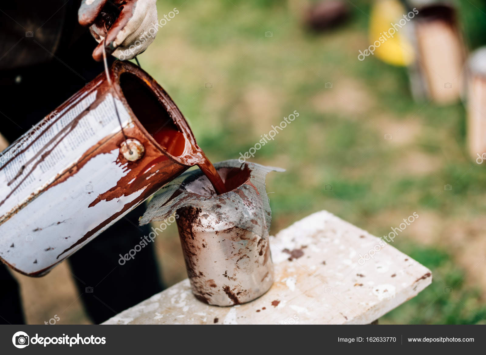 Construction worker wearing protective gloves pouring liquid paint into ...