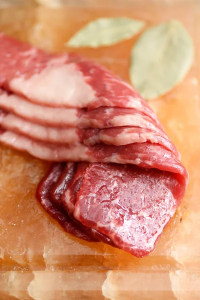 Salt block cooking. Close up of thin slices of meat served on bi ...