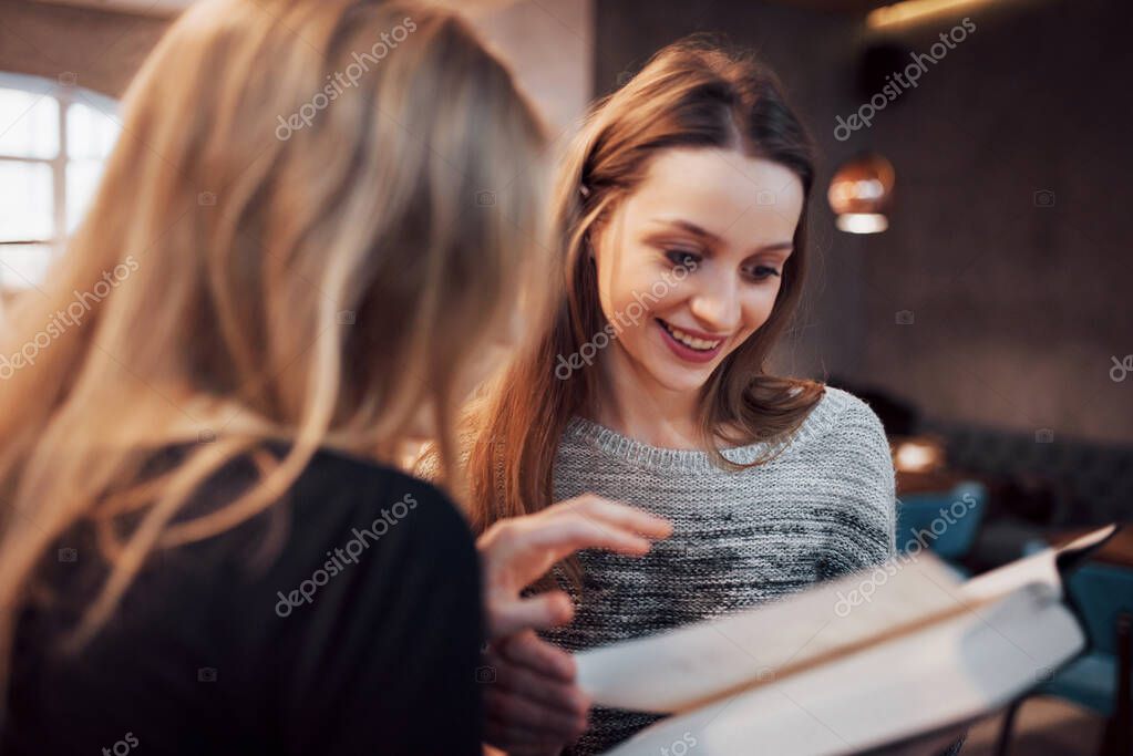 Two Girl está absorta en leer libros durante la pausa en la cafetería ...