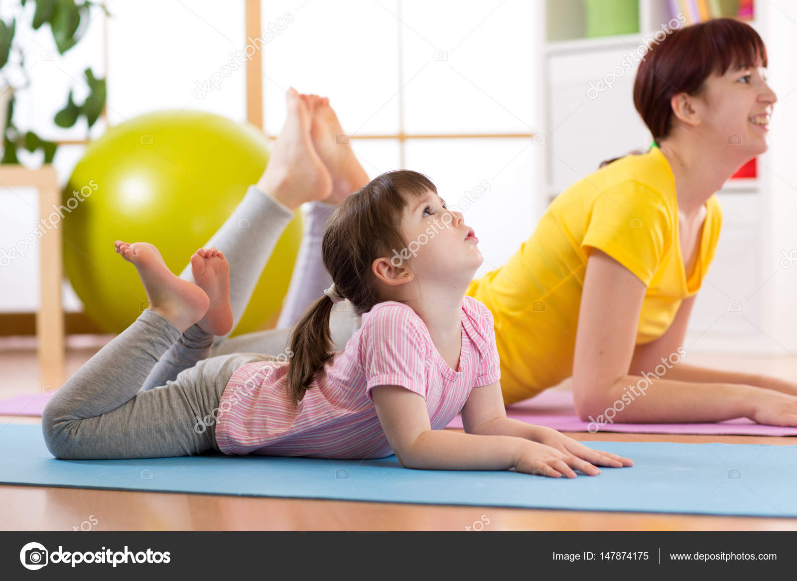 Mother And Daughter Doing Gymnastics Exercises On Mat At Home Stock