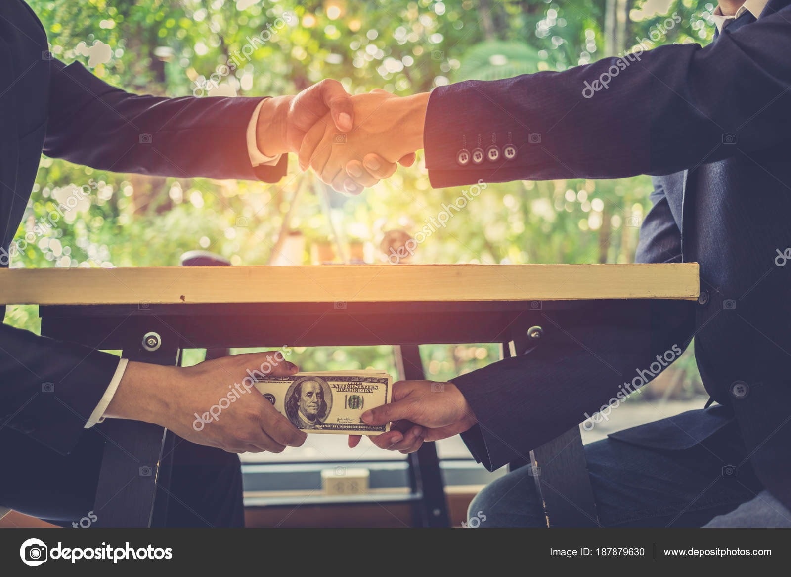 Corrupted two businessman sealing the deal with a handshake and ...