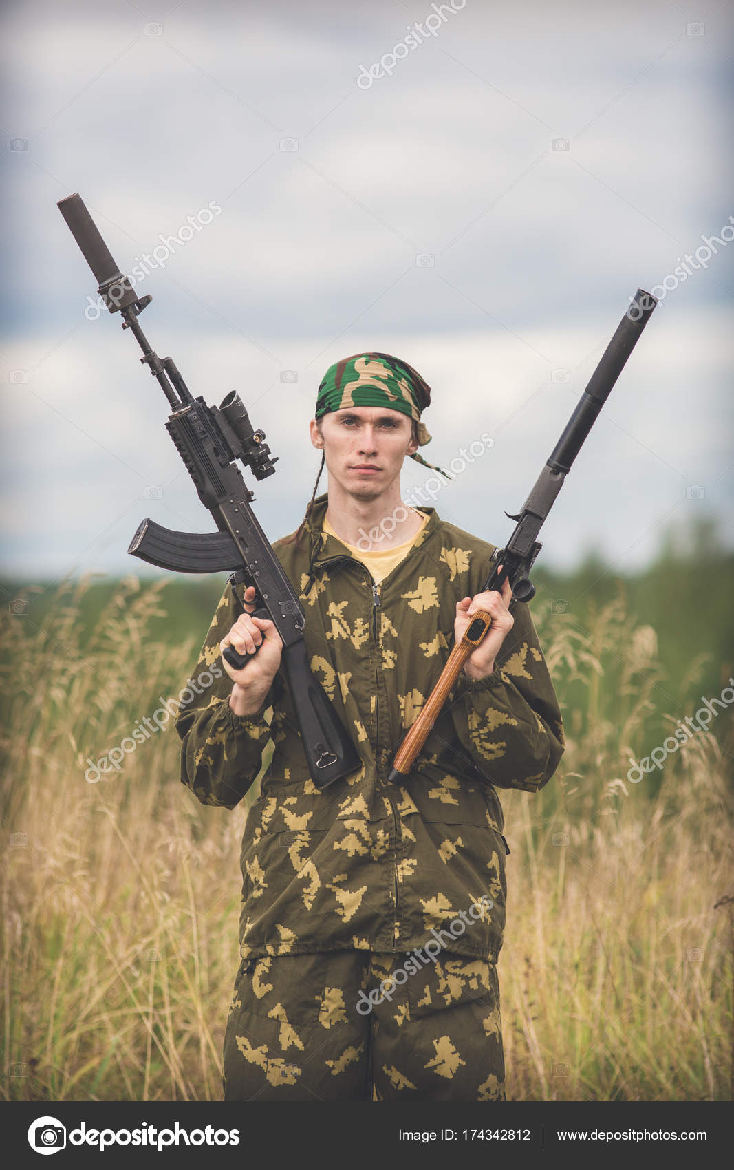 A man with weapons in both hands standing in a field — Stock Photo ...
