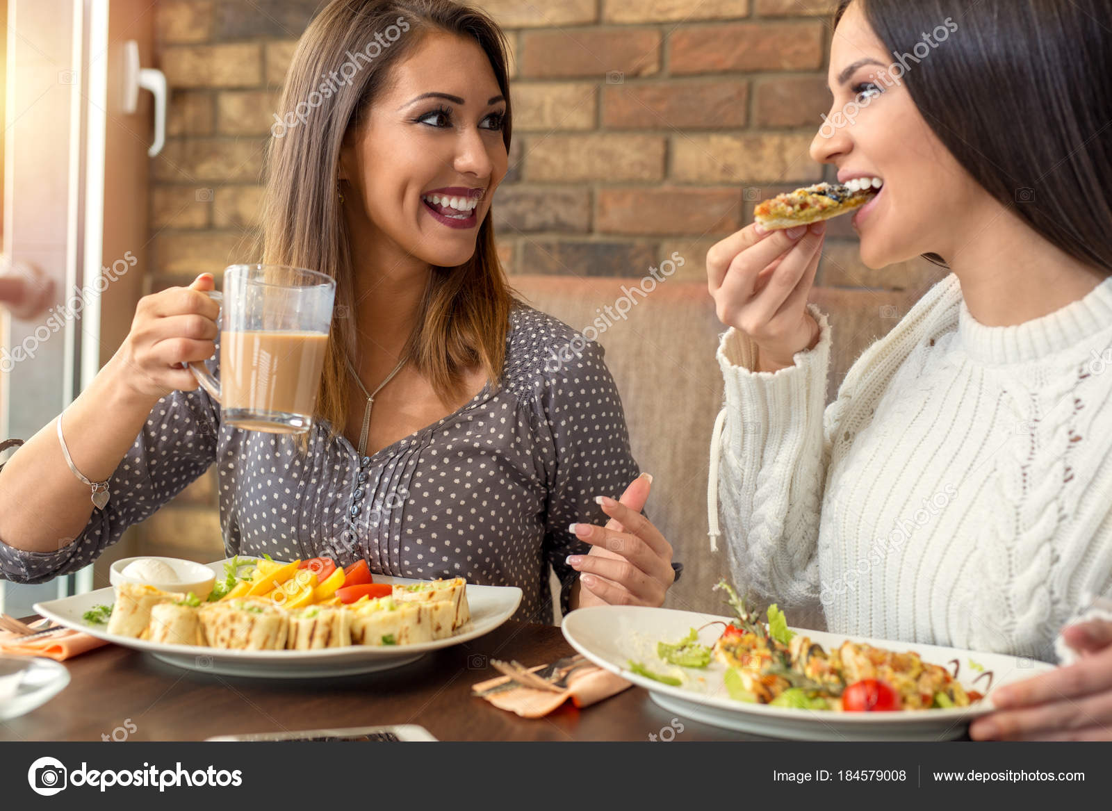 Two girlfriends having lunch together at a restaurant Stock Photo by ...