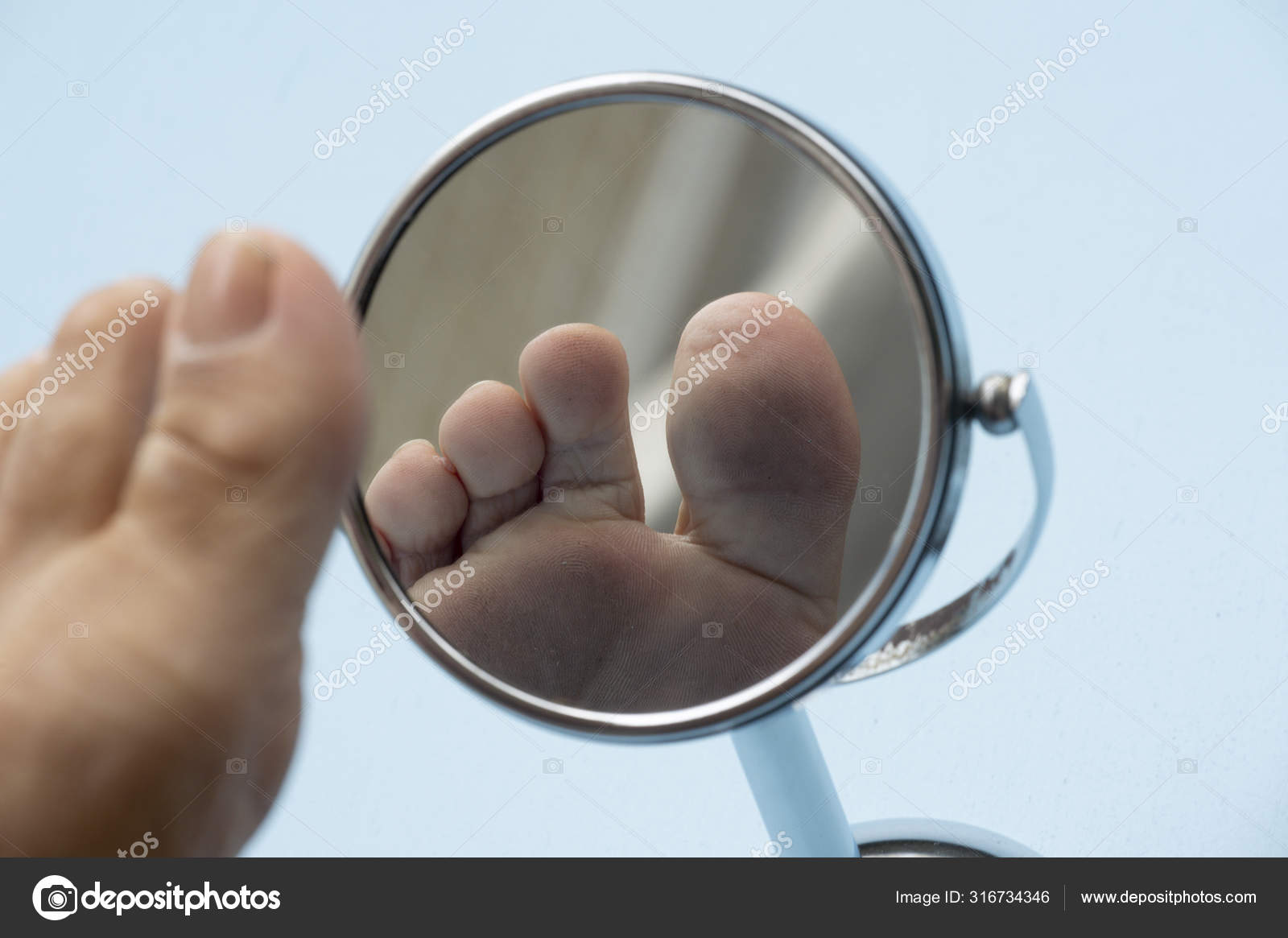 Person looking at the sole of the foot in a mirror. Stock Photo by ...