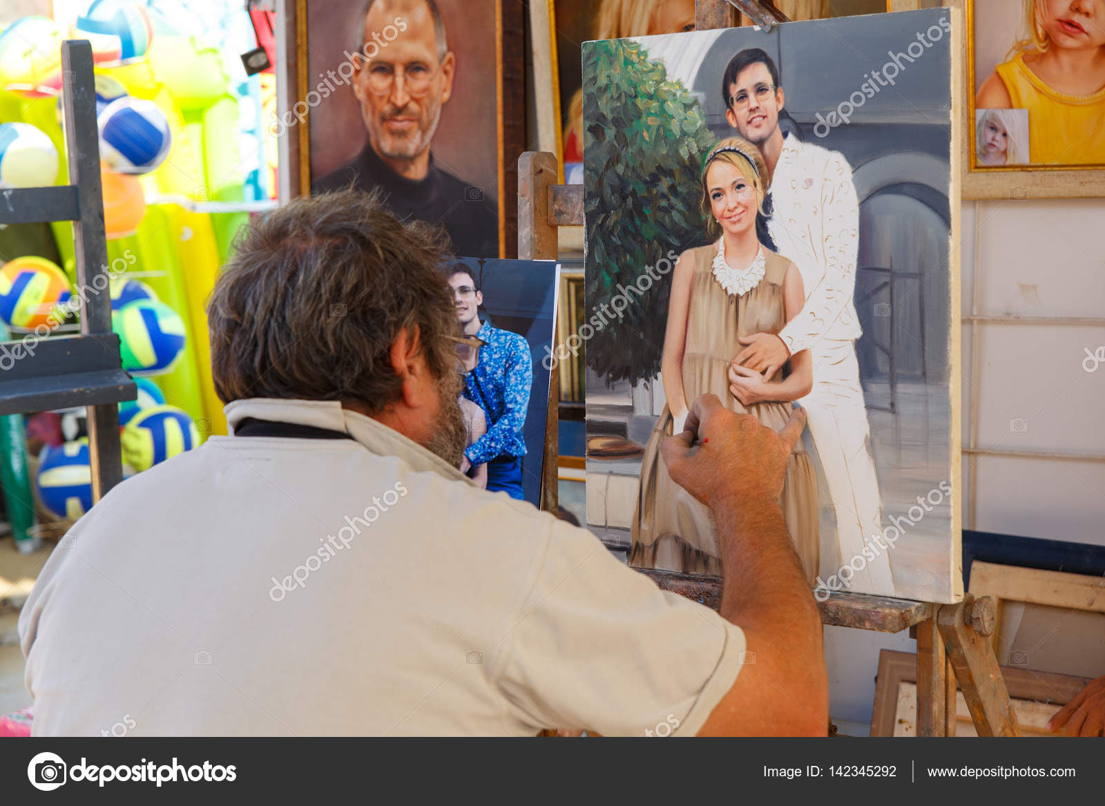 Street painter makes a copy from photo of young couple on canvas ...