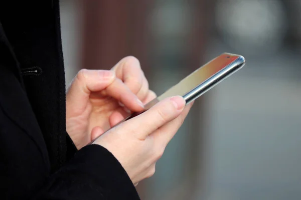 Woman using smartphone on a street. Close up of female hands with ...
