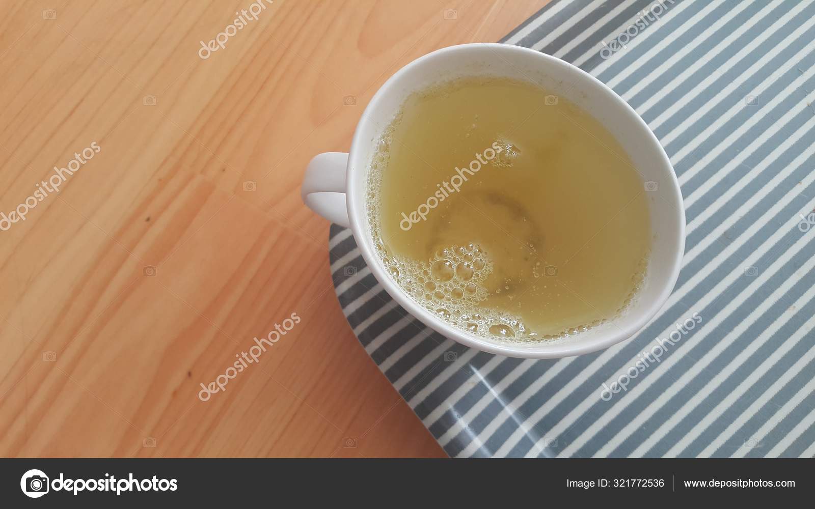 Top view of green tea in a cup placed in a tray over a wooden floor ...