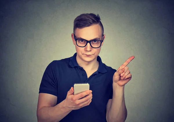 Man with smartphone showing no, attention with finger hand gesture ...