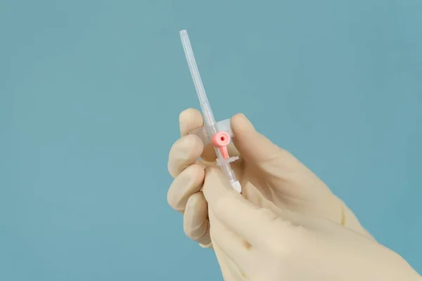 catéter gotero en las manos de un médico sobre un fondo azul 2024