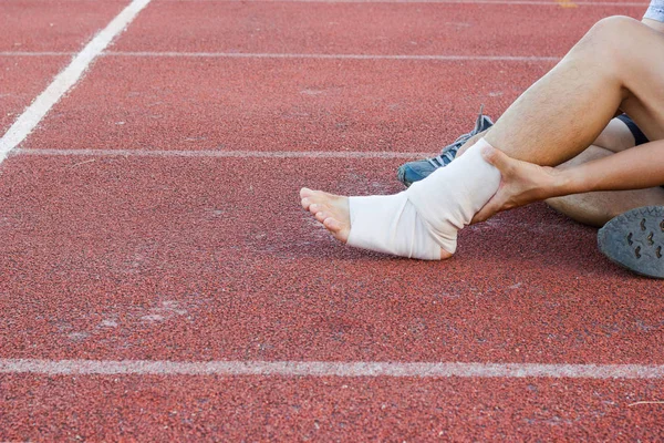 Male athlete applying compression bandage onto ankle injury of a ...