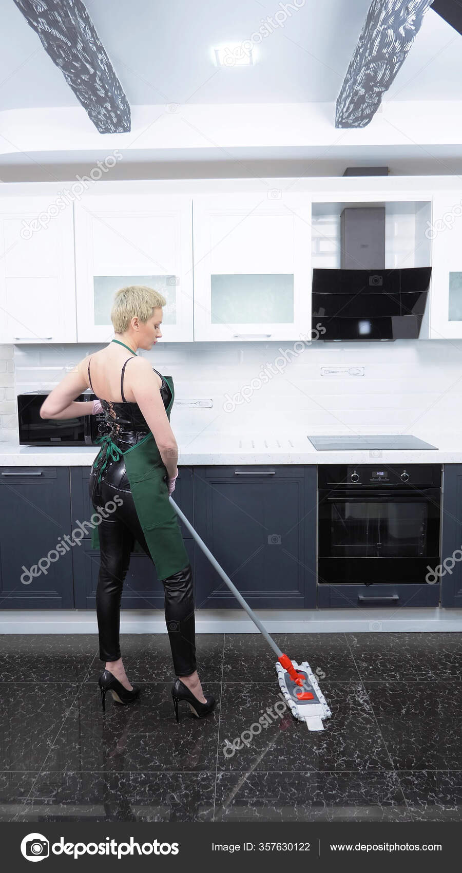 Vertical shot. a woman in a leather corset and apron washes the floor ...