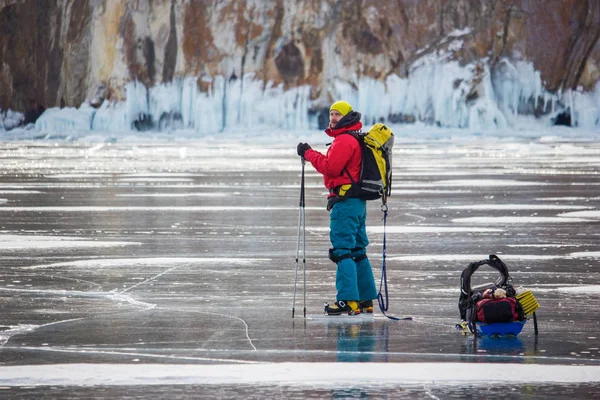 man with backpack going through ice water surface and hills on ...