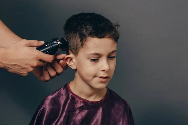 Boy at the barber shop to cut the hair. Cute young boy getting a ...