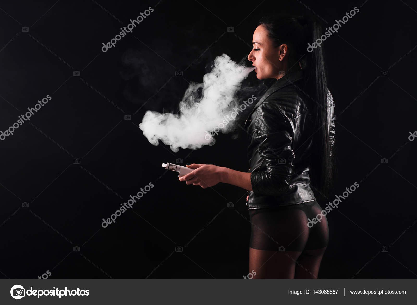 Young beautiful brunette woman smoking, vaping e-cigarette with smoke ...