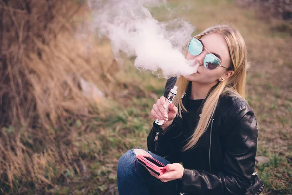 Vaping. Young beautiful woman smoking ( vaping ) e-cigarette with smoke ...