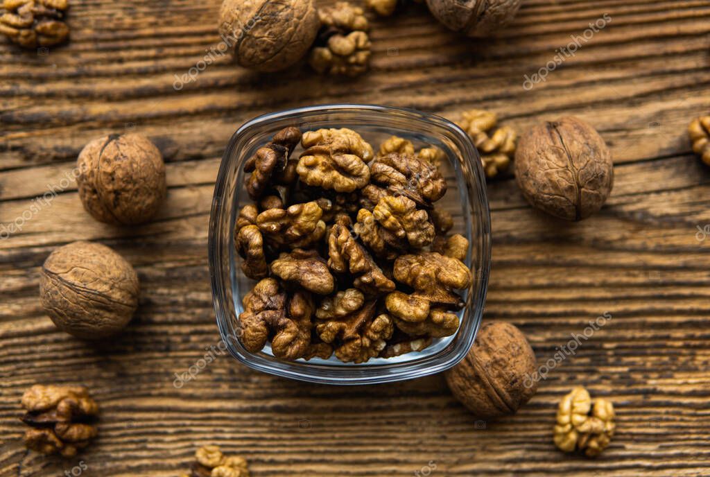 Nuez en un plato smale con nueces esparcidas con cáscara y nuez entera ...