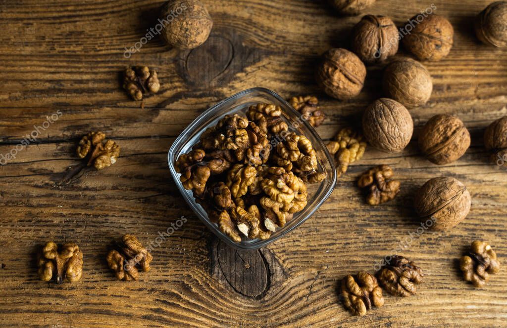 Nuez en un plato smale con nueces esparcidas con cáscara y nuez entera ...