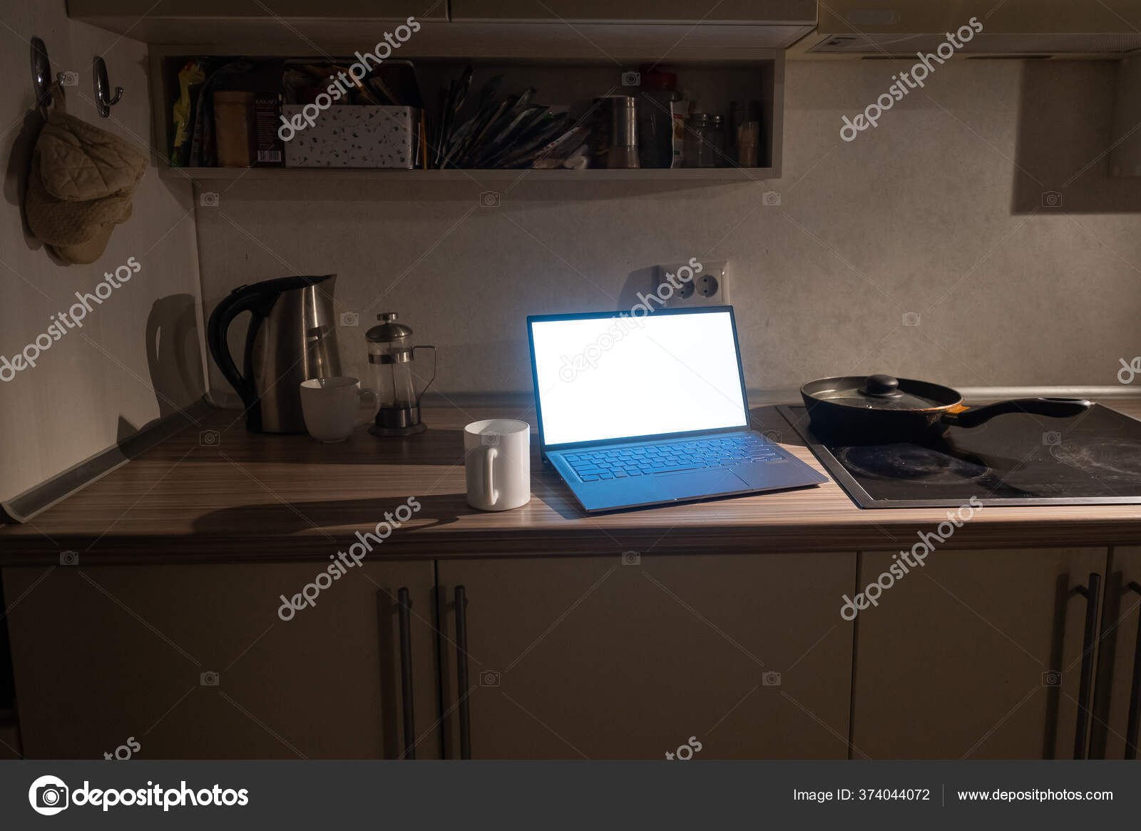 A working laptop with a white screen stands on the kitchen table next ...