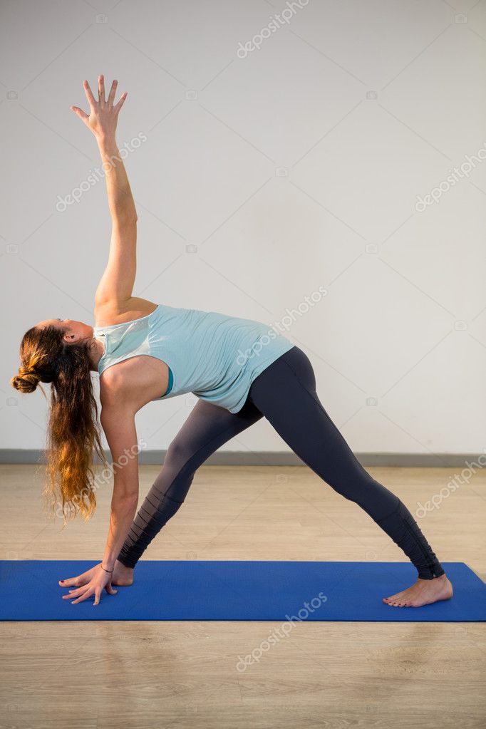 Woman performing triangle pose Stock Photo by ©Wavebreakmedia 126937060