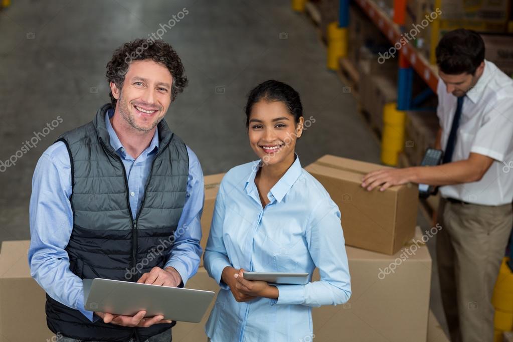 Warehouse workers using laptop and digital tablet — Stock Photo ...