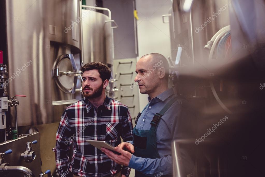 Owner and worker examining machinery Stock Photo by ©Wavebreakmedia ...