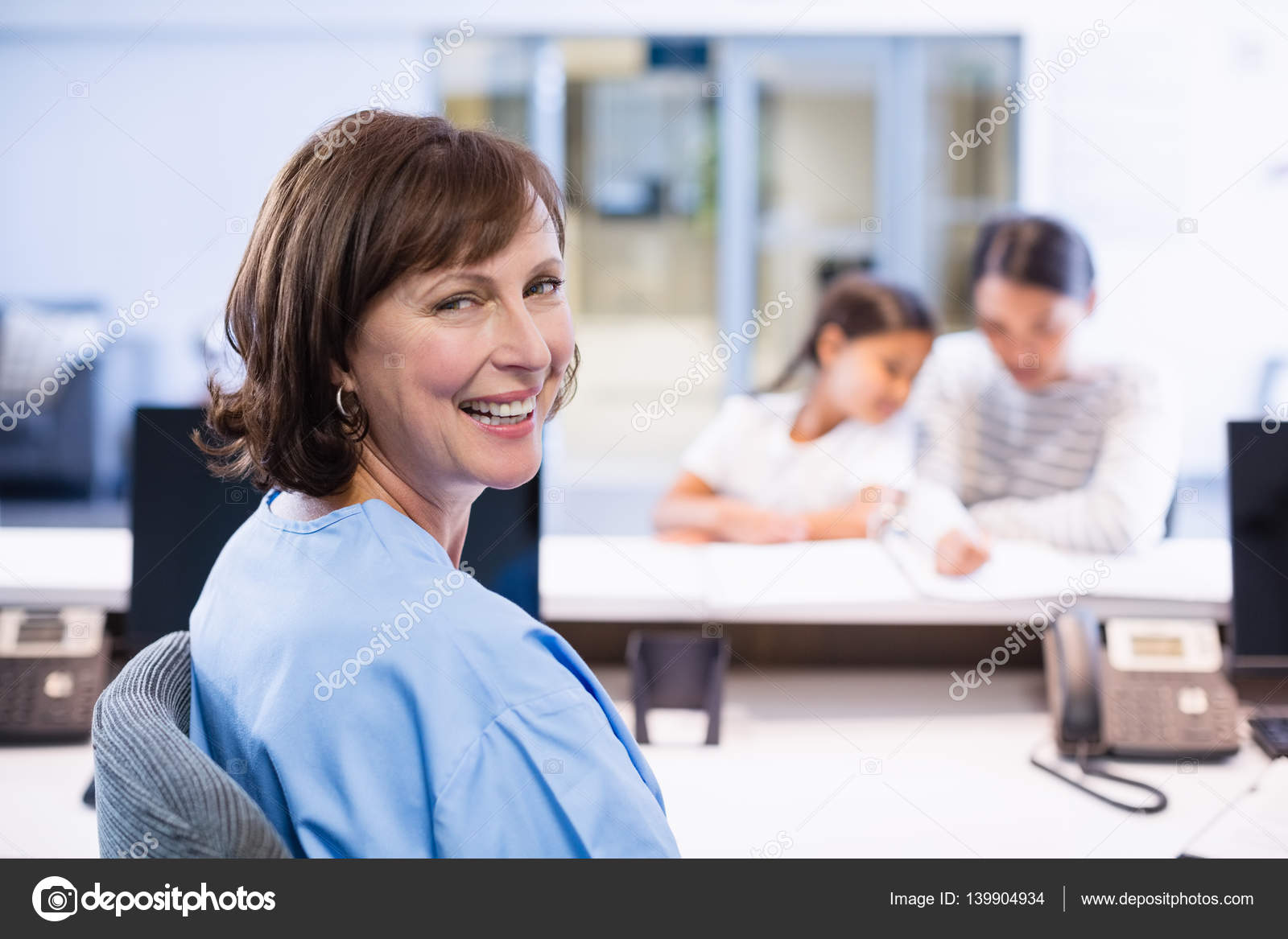 Portrait of smiling nurse sitting at desk Stock Photo by ...