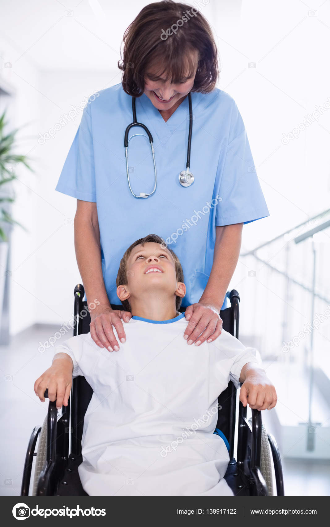Doctor pushing disable boy in hospital corridor Stock Photo by ...