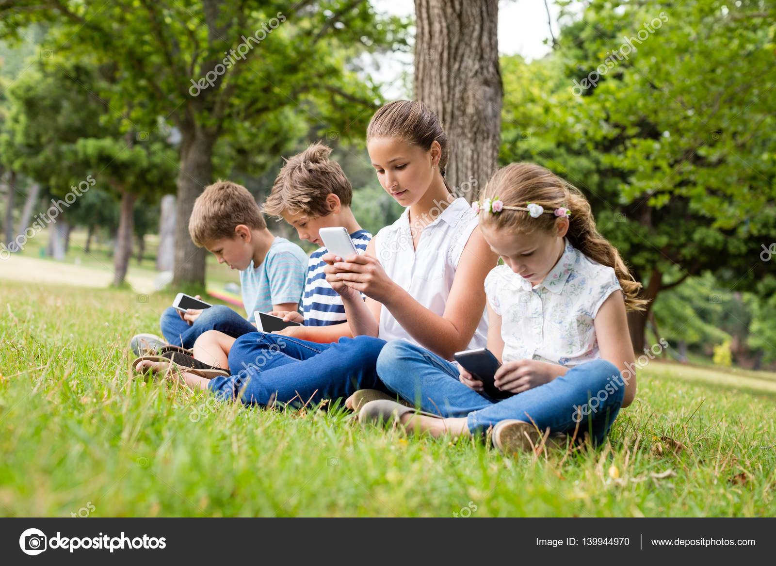 Kids using mobile phone in park Stock Photo by ©Wavebreakmedia 139944970