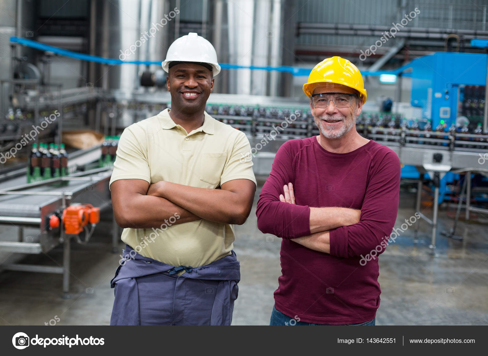 Two factory workers standing with their arms crossed in drinks ...