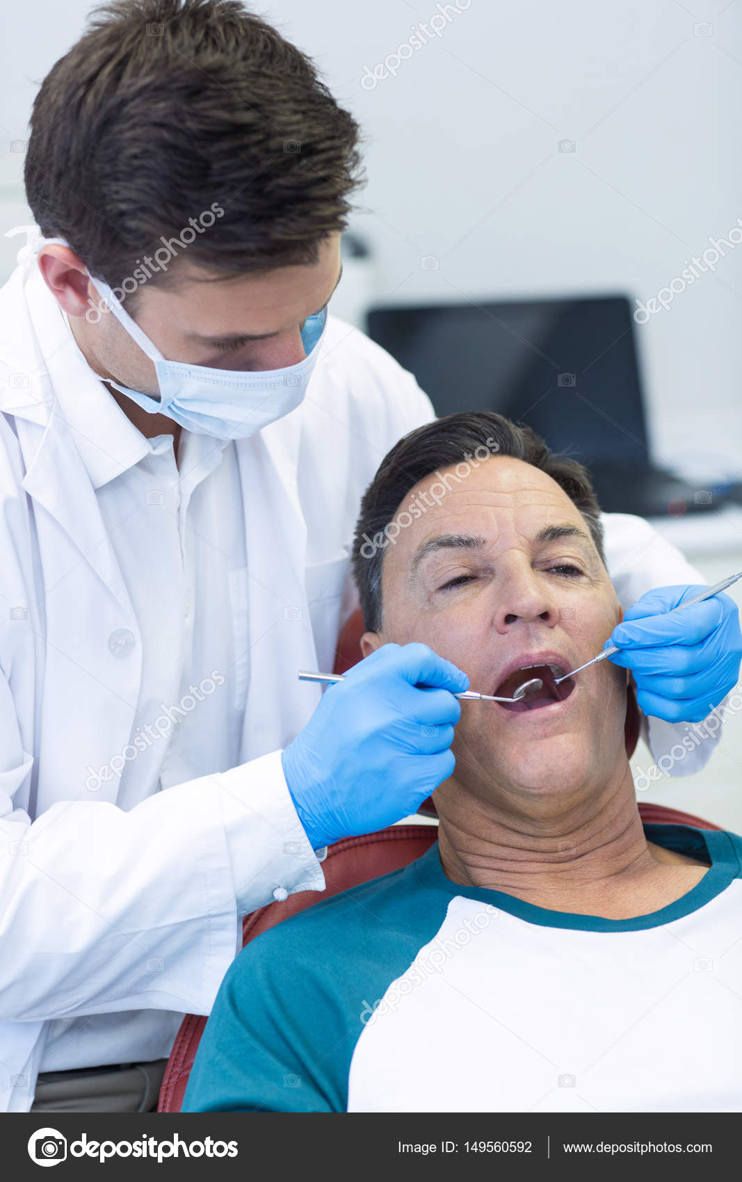Dentist examining a male patient with tools — Stock Photo ...