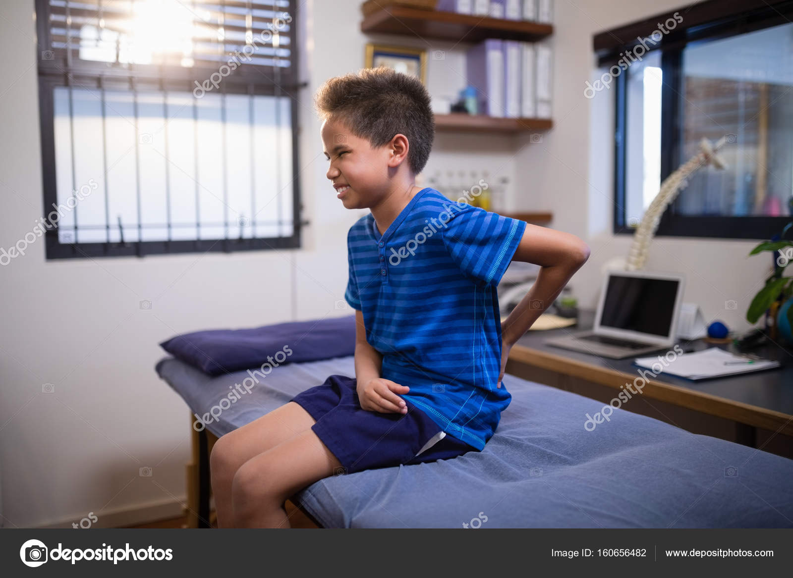 Boy frowning with backache Stock Photo by ©Wavebreakmedia 160656482