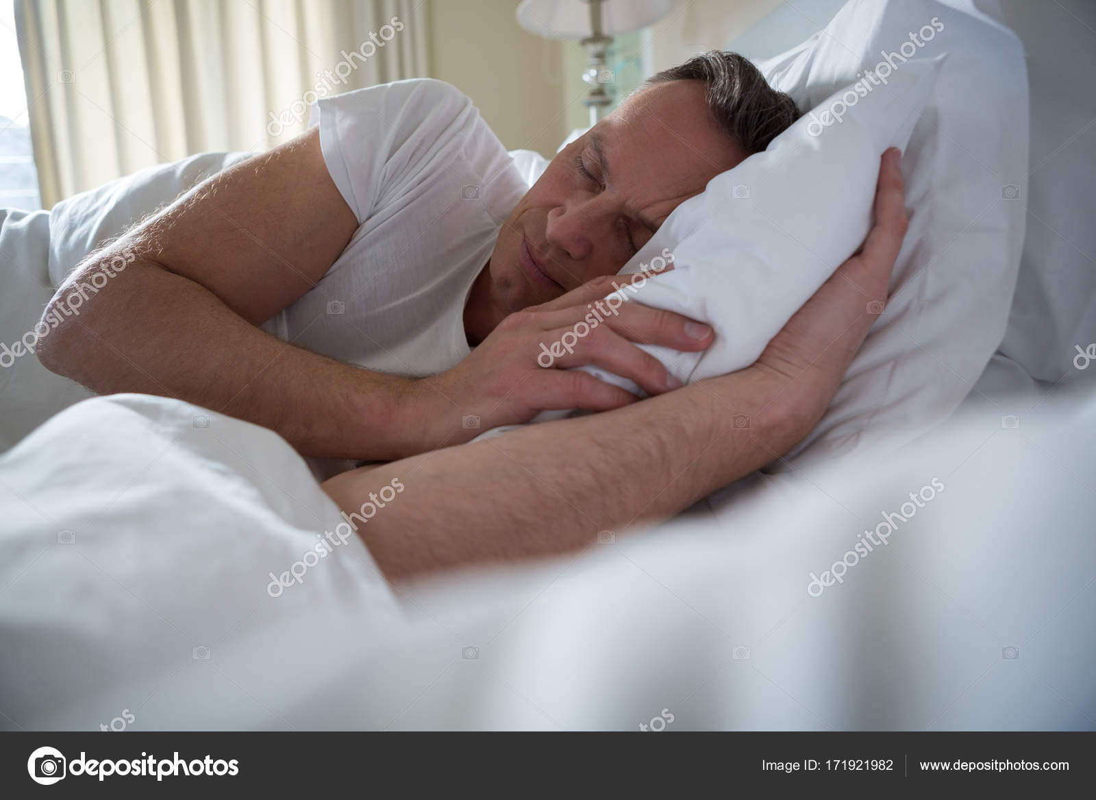 Man sleeping on bed in bedroom Stock Photo by ©Wavebreakmedia 171921982