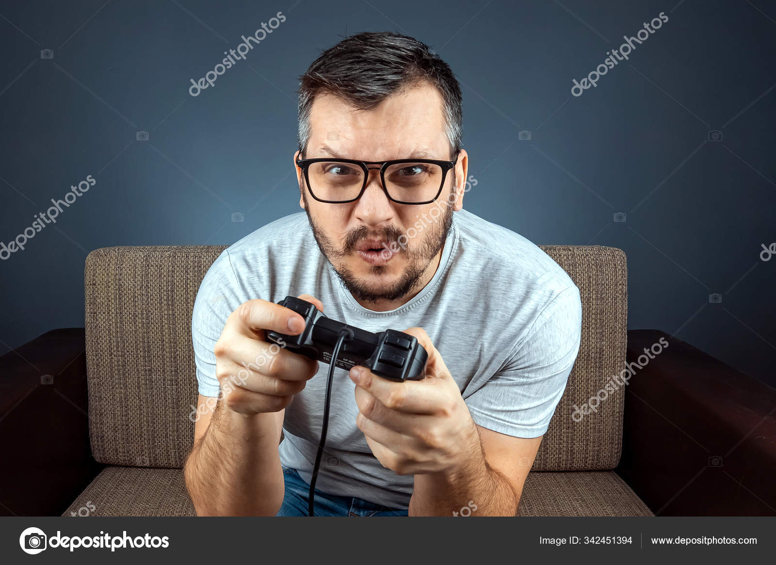 A man plays a video game console while sitting on a sofa. Day off ...