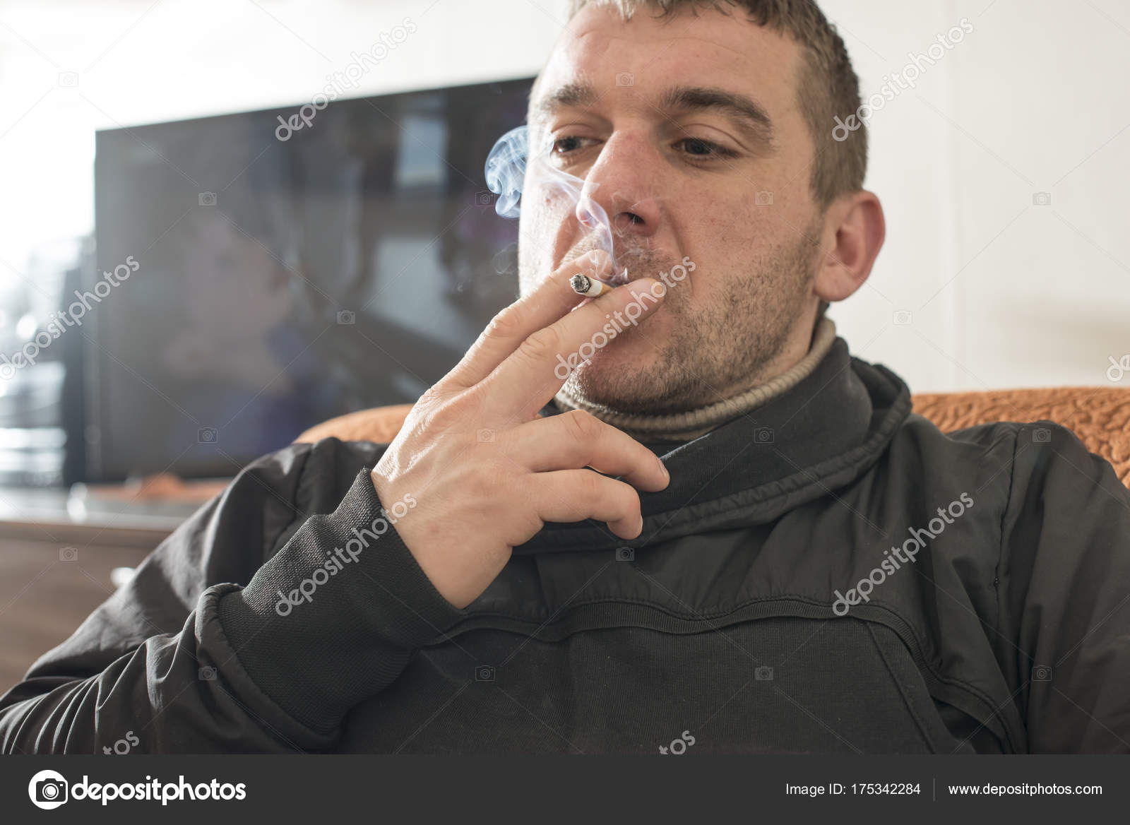 Man smokes a cigarette in the house. — Stock Photo © degimages #175342284