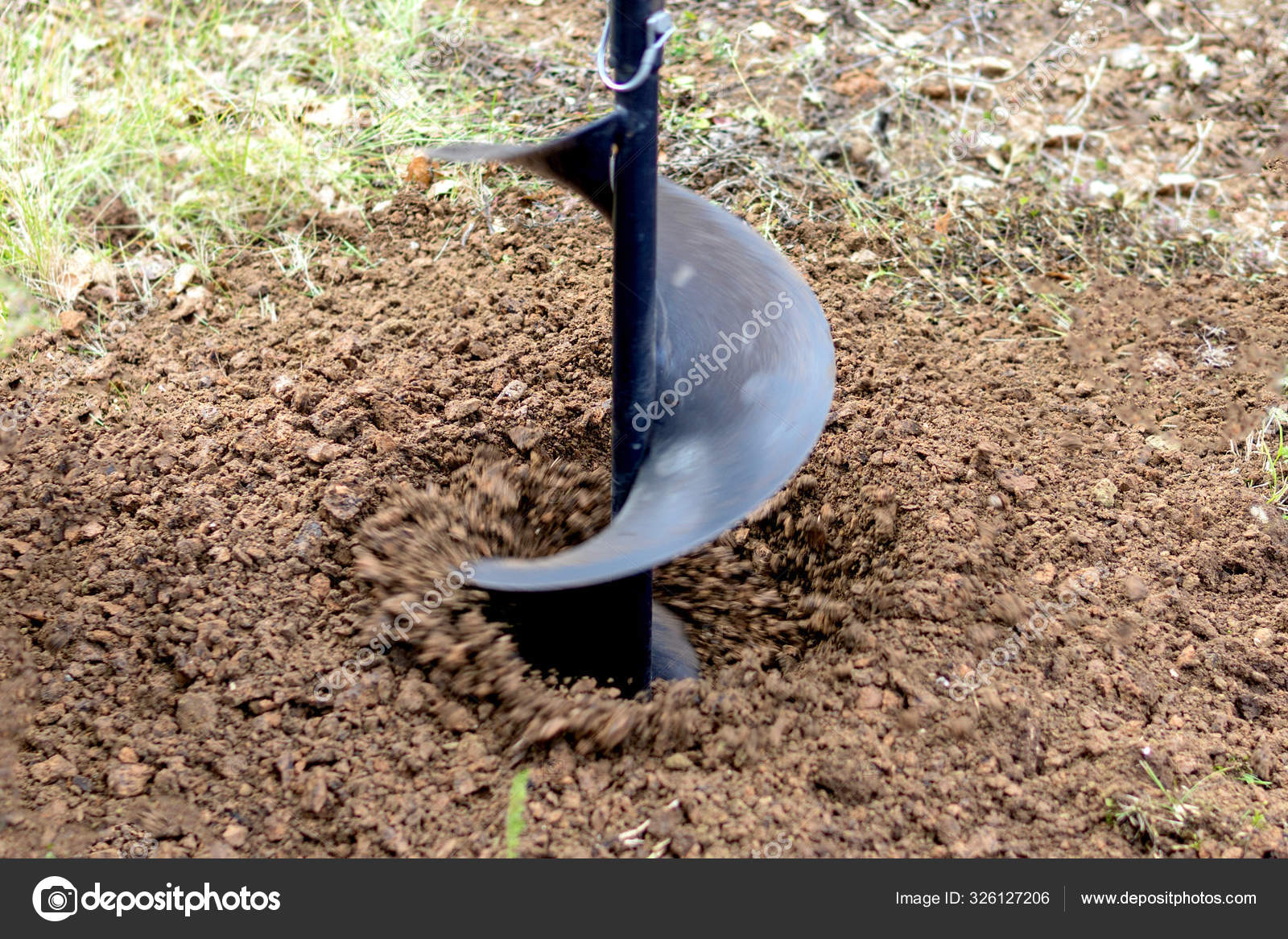 The drill rotates and falls into the ground. Pieces of land are flying ...