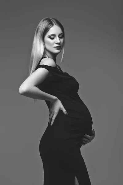 Pregnant Woman In Black Dress On Gray Background A Few Days Before
