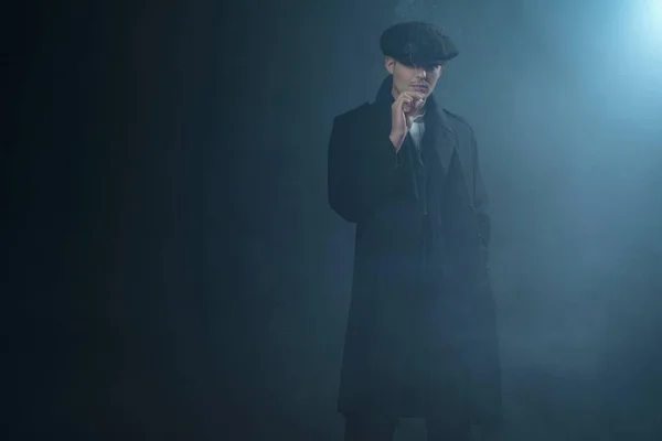 Gangster in flat cap in smoky room. Stock Photo by ©ysbrand 139812910