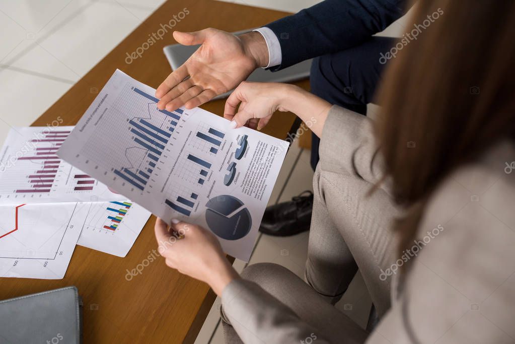 Retrato de alto ngulo de dos empresarios que discuten datos estad sticos en la oficina, se ...