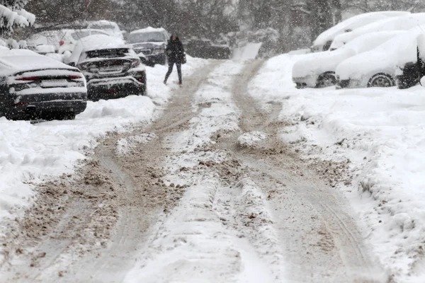 Winter. People walk on a very snowy sidewalk and road. People step on ...