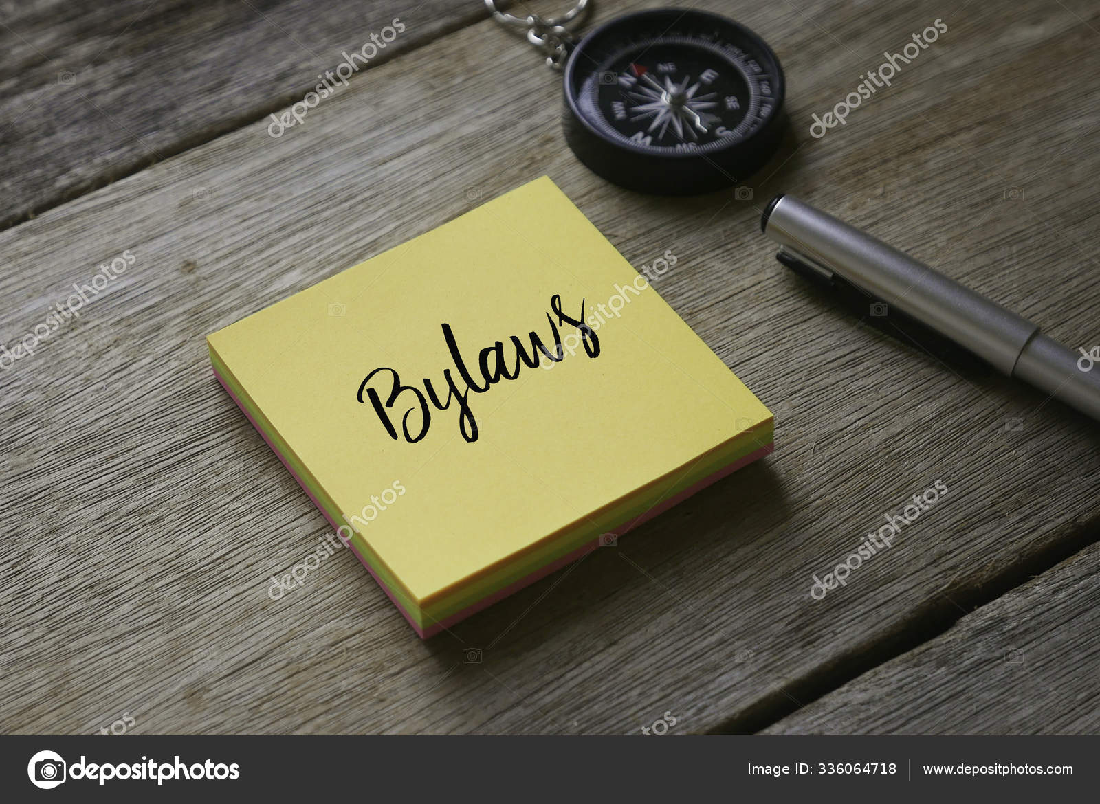 Compass,pen and yellow sticky notes written with Bylaws on wooden ...