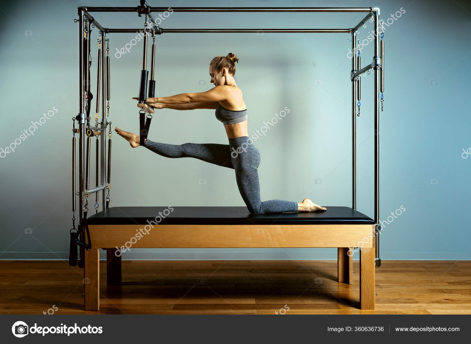 Young girl doing pilates exercises with a reformer bed. Beautiful slim ...