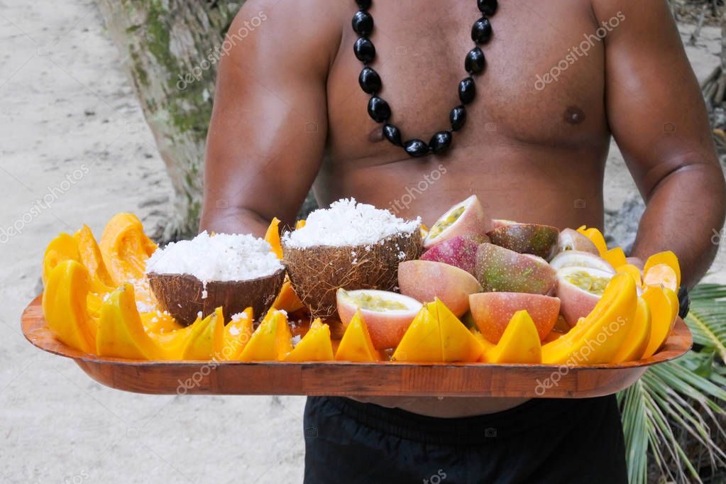 El hombre de las Islas Cook sirve coco y papaya en una bandeja en R 2023