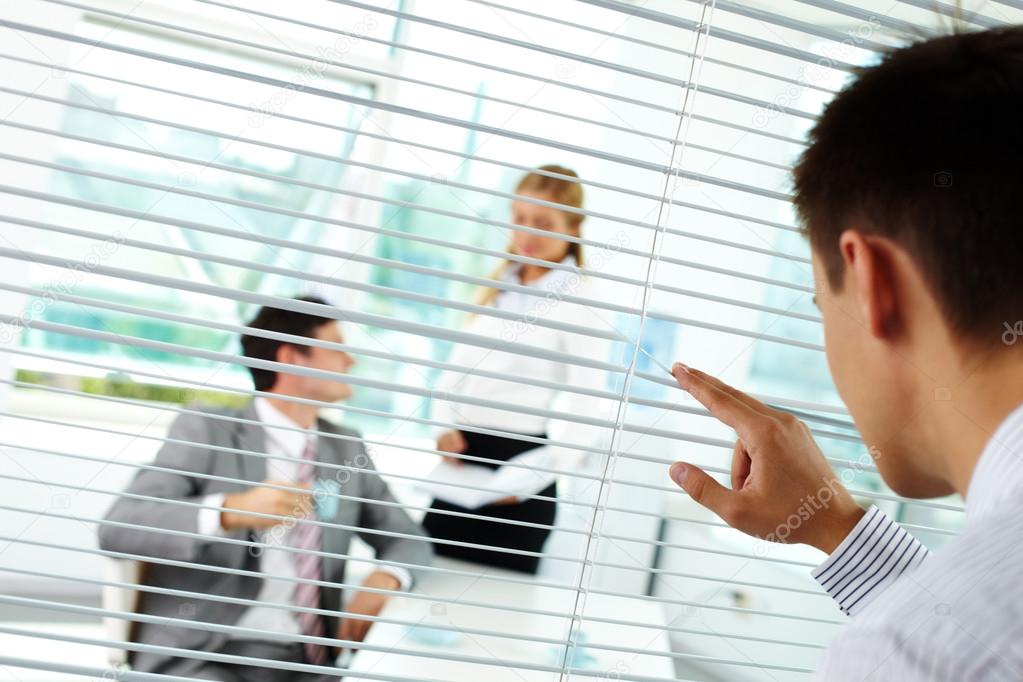 Businessman looking through blinds at his colleagues — Stock Photo ... Businessman looking through blinds at his colleagues — Stock Photo ...