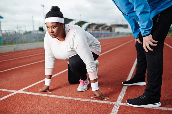 Young oversized sporty woman standing by start line ready to run with ...