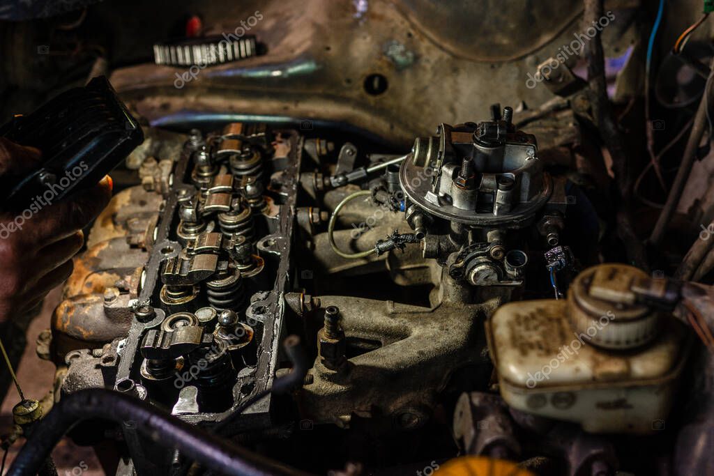 Un mecánico enciende una linterna en un motor defectuoso en un servicio ...
