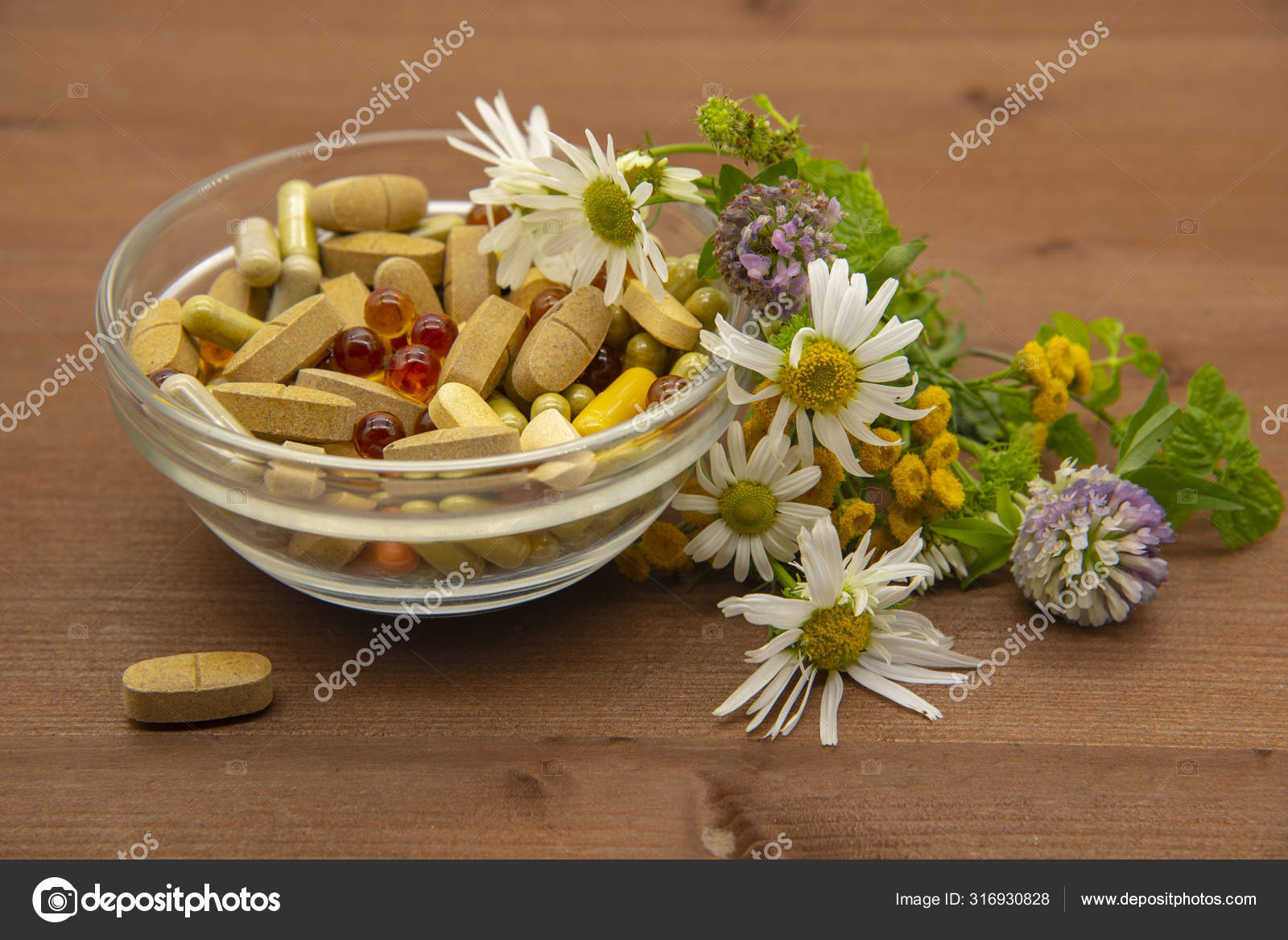 A bowl with various capsules and tablets, medicinal and aromatic herbs ...
